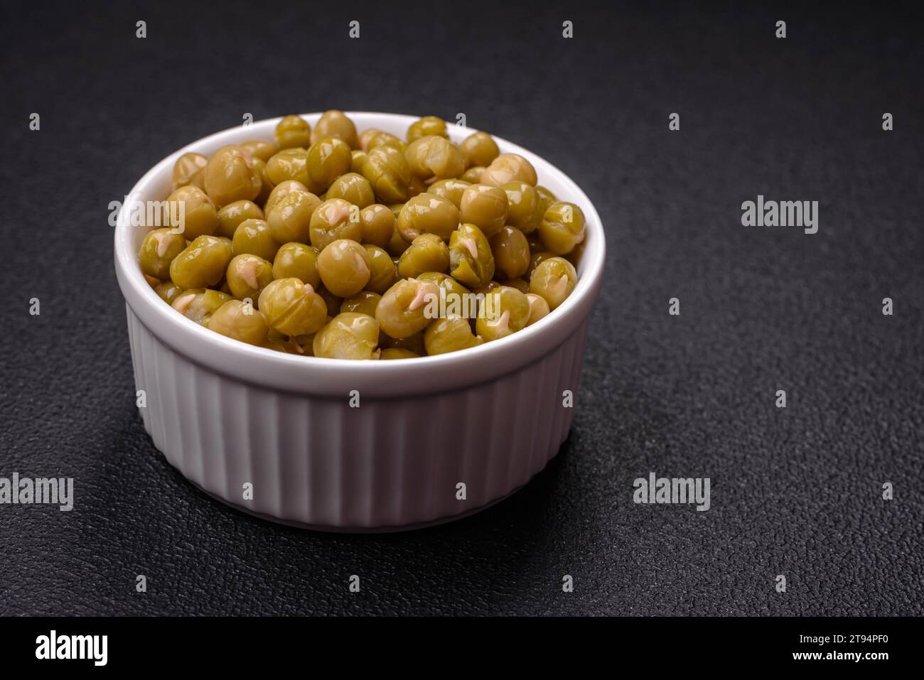 Delicious canned green peas with salt and spices in a white bowl on a ...
