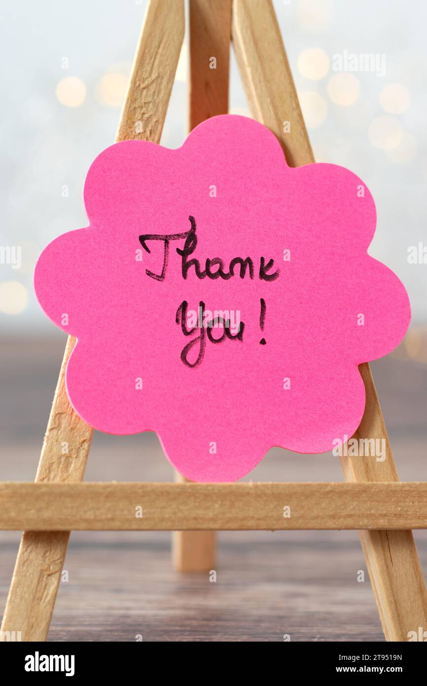 Thank you text handwritten on pink sticky note in flower shape with ...