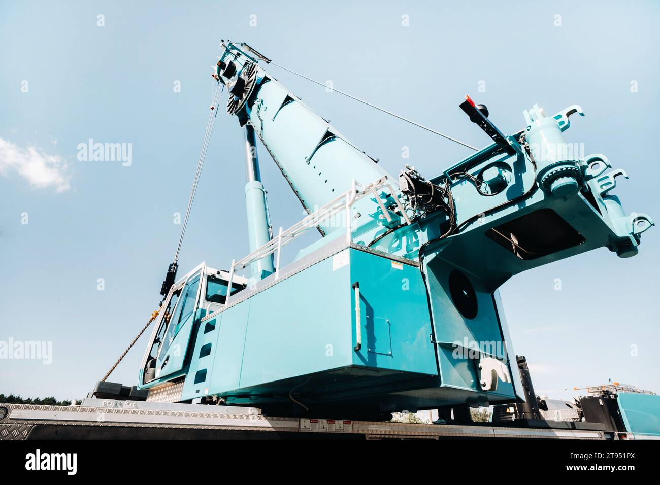 a cab with the operator of a Large blue car crane that stands ready to ...
