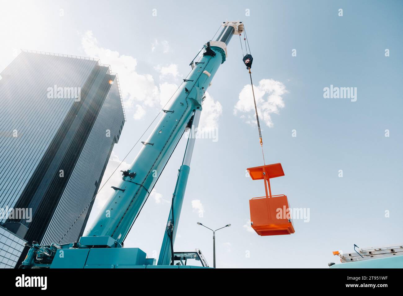 A large blue truck crane stands ready for operation on a site near a ...