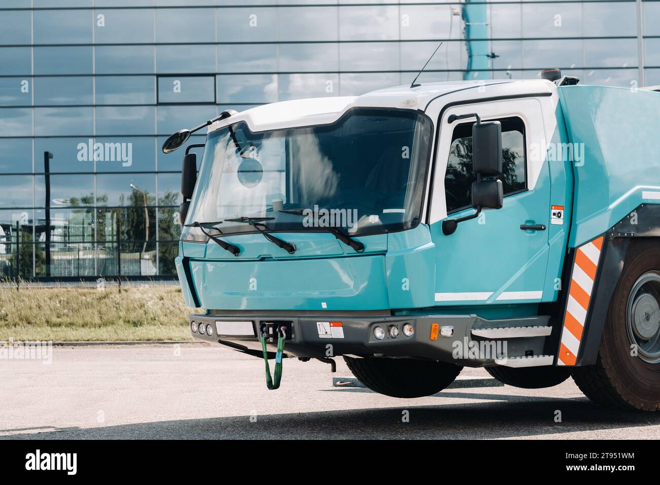 A large blue truck crane stands ready to operate on hydraulic supports ...