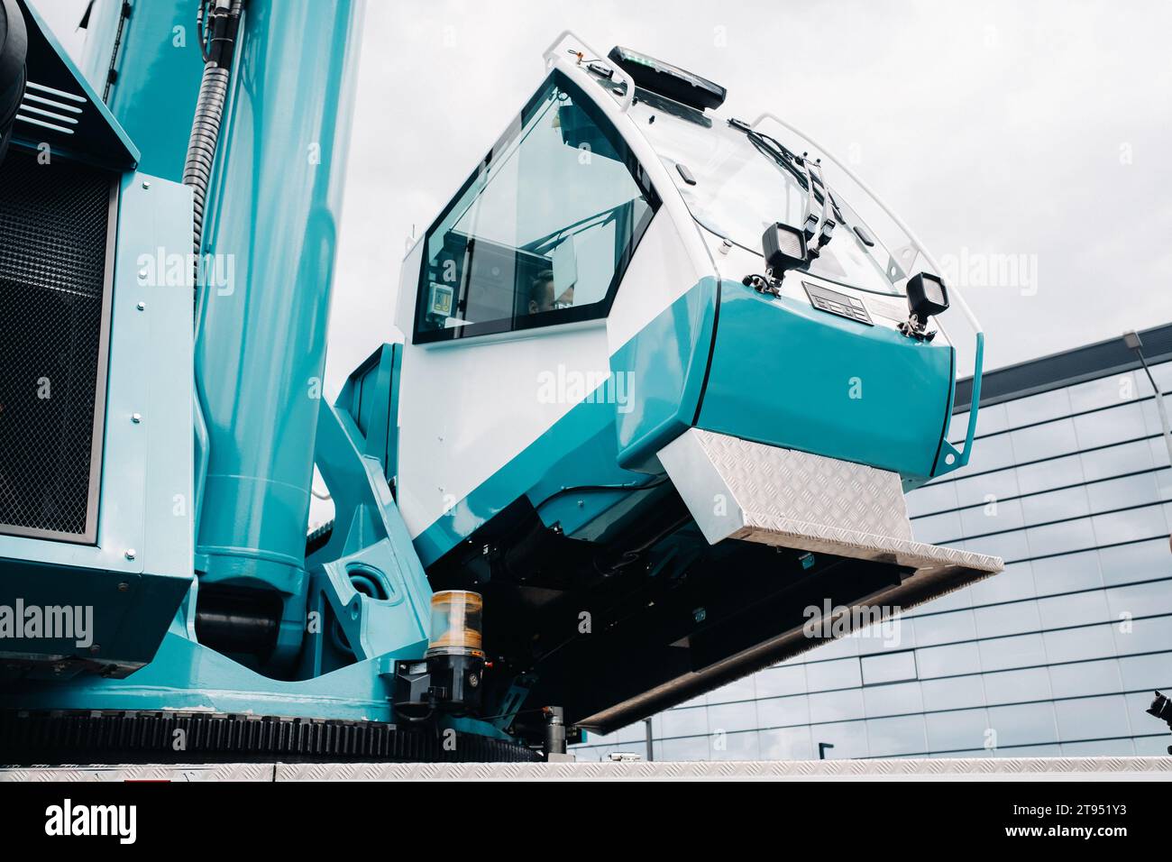 a cab with the operator of a Large blue car crane that stands ready to ...