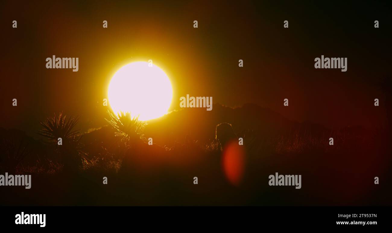 Mighty orb of the late-day sun sets beyond a nearby hill top with ...
