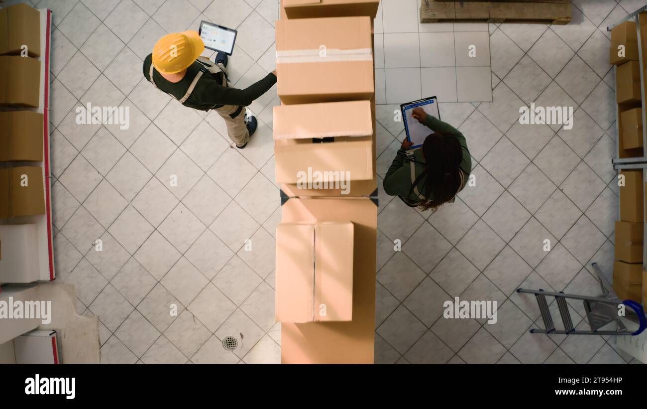 Top down view of warehouse logistics coordinators examining cardboard ...
