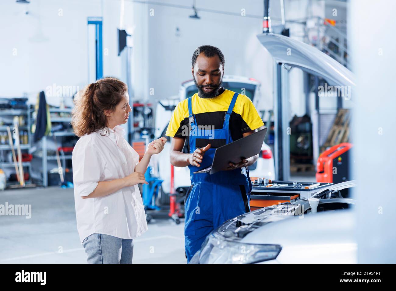 Mechanic in car service uses laptop to calculate invoice for client ...