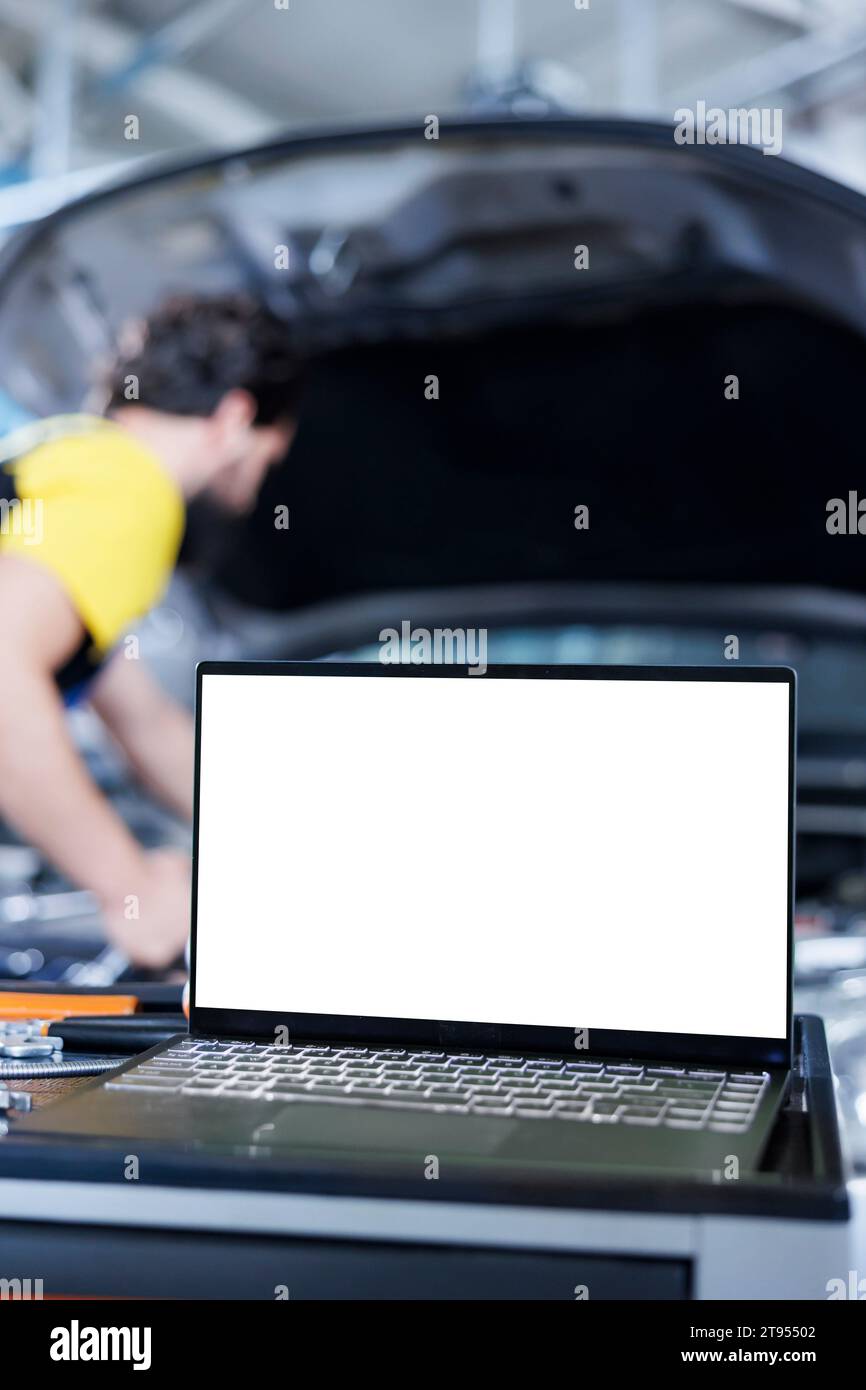 Mockup laptop on car service work station bench with repairman in ...