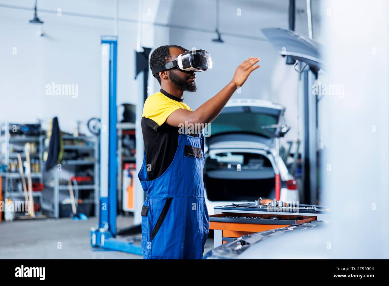 BIPOC repairman in auto repair shop using virtual reality to visualize ...