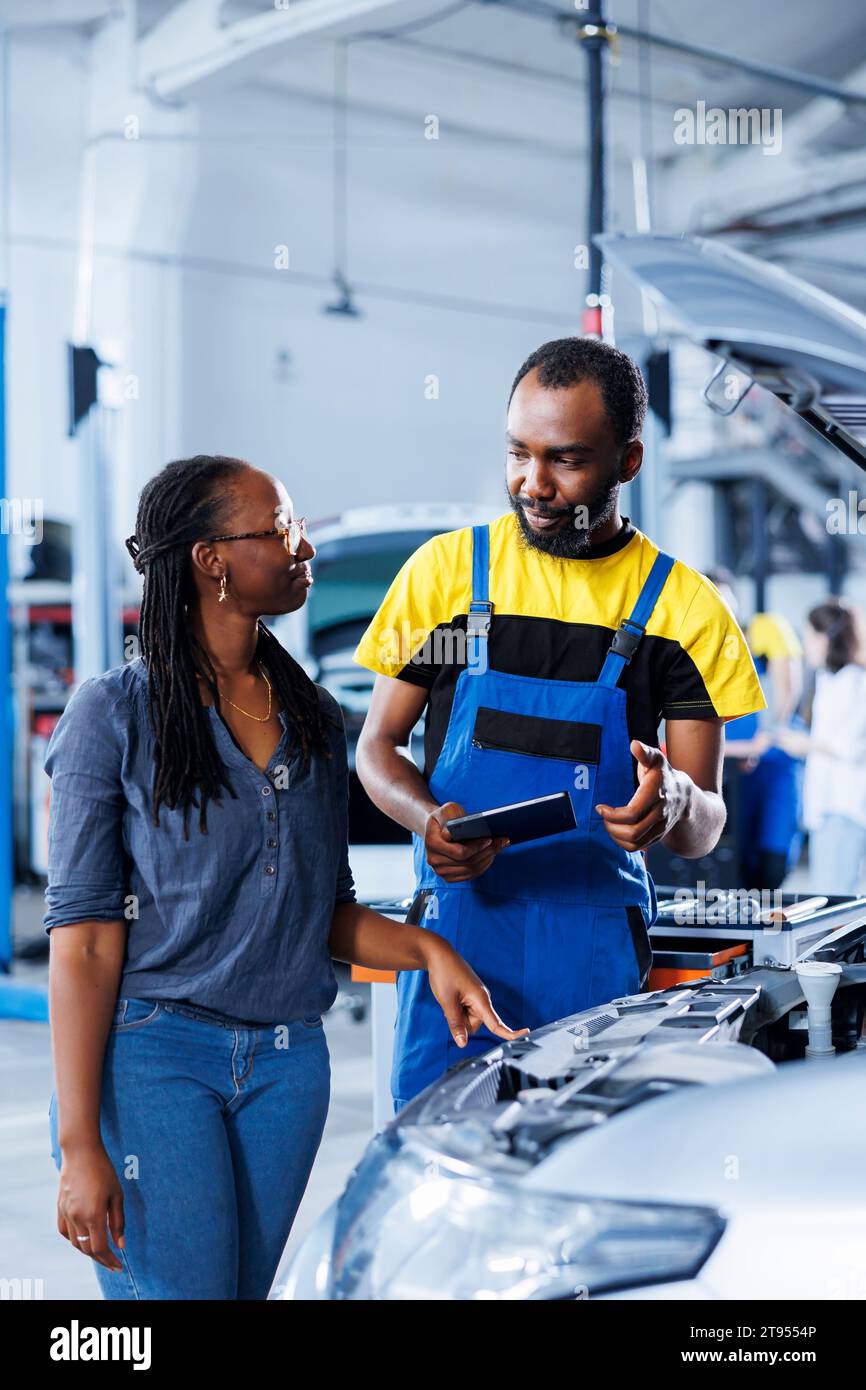 Mechanic in car service uses tablet to calculate invoice after fixing ...