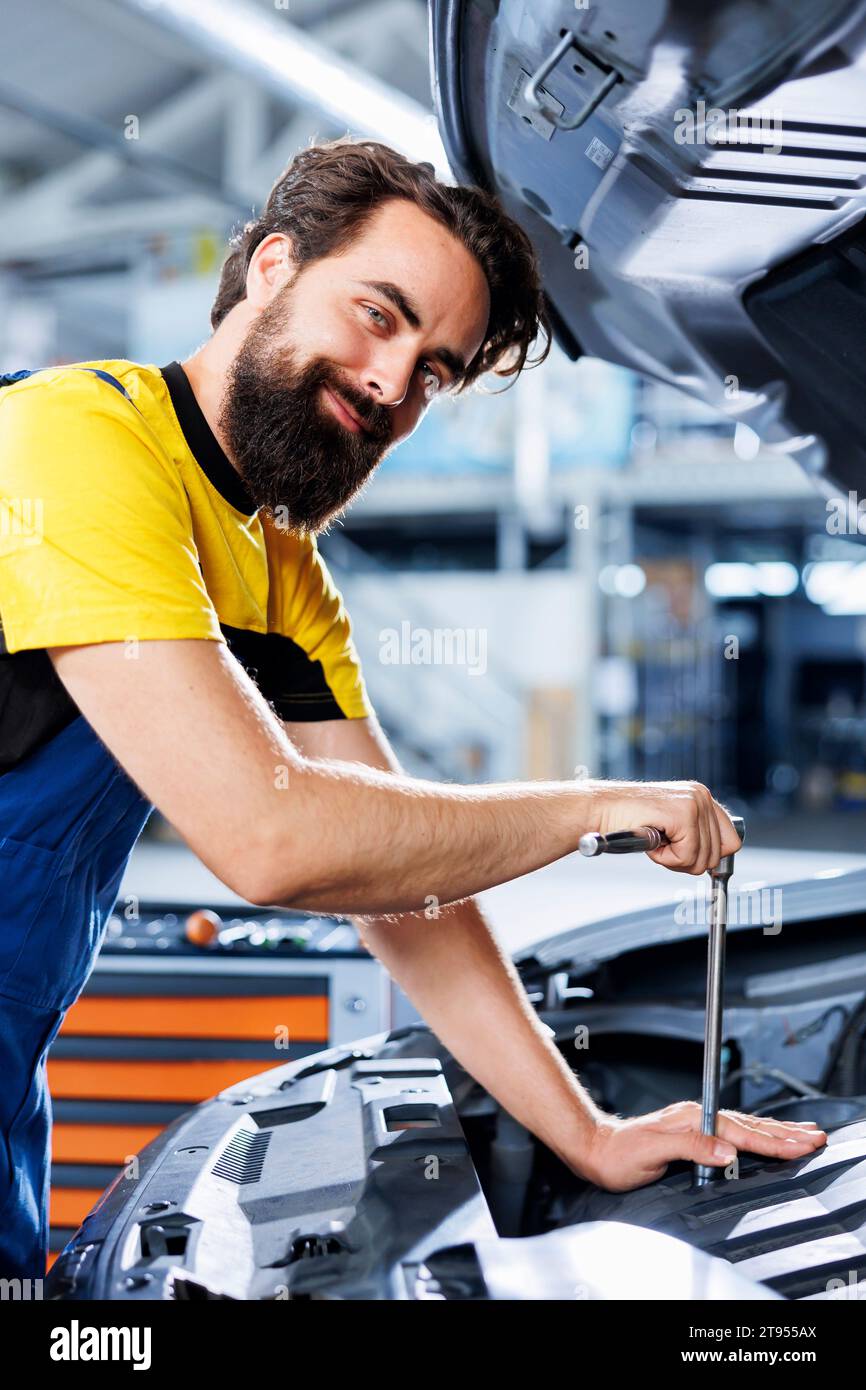 Portrait of smiling repairman in car service uses torque wrench to ...