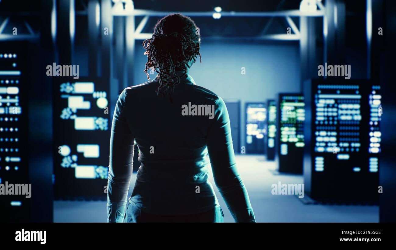 Skillful employee strolling around data center server rows, looking for damages in high tech ...