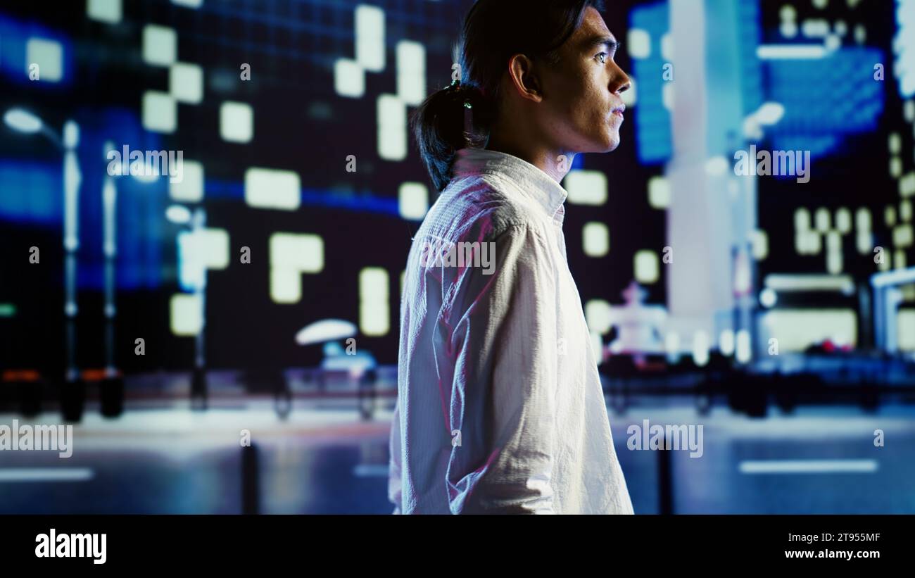 Asian man wandering around city streets at night, looking upwards to ...