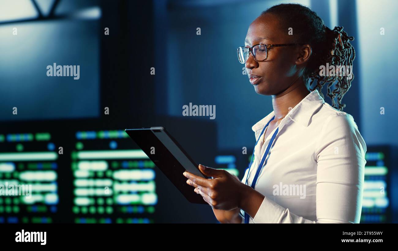 African american woman walking through server farm rows providing ...