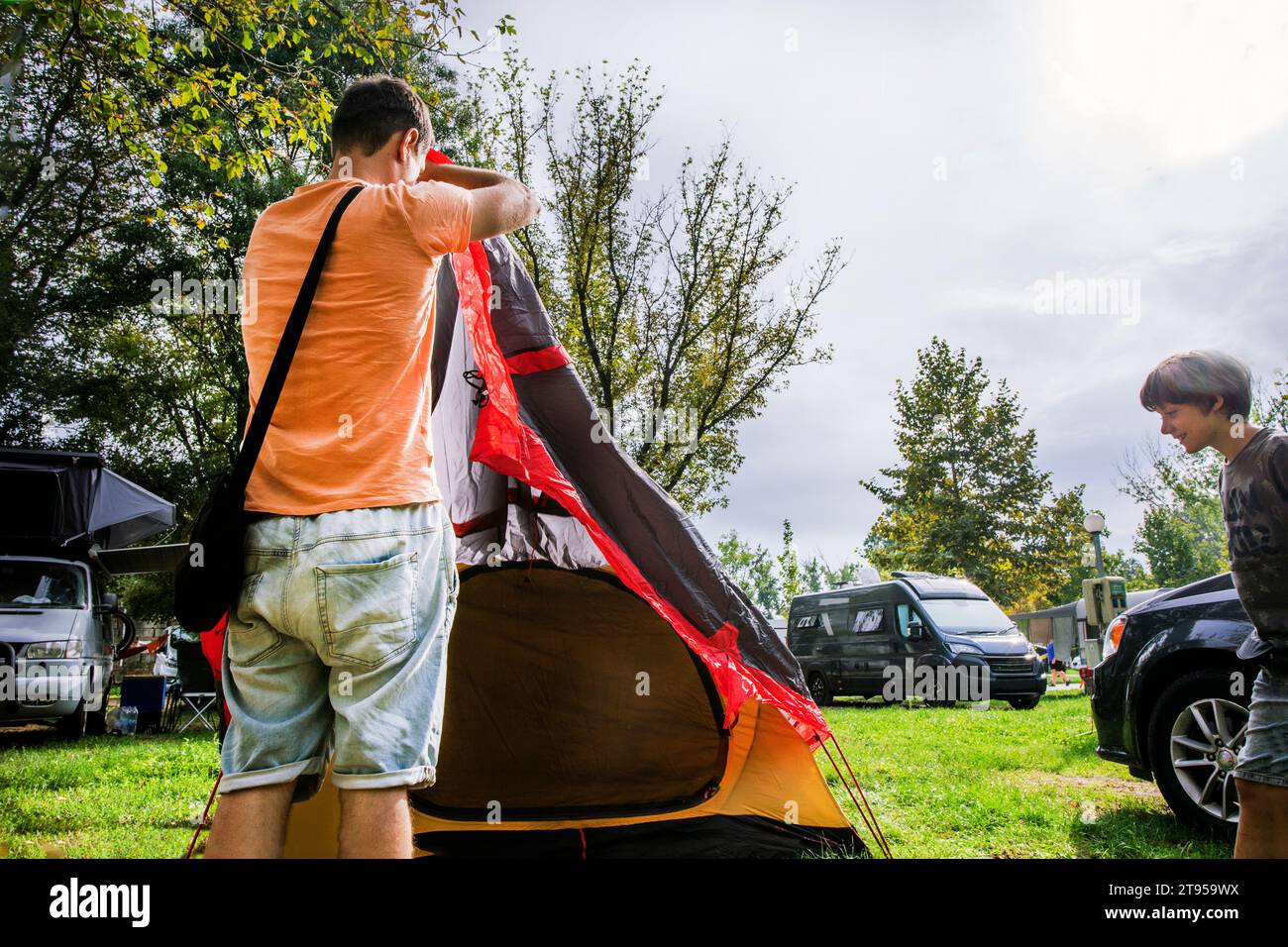 Happy dad and son cover a tent with an awning at a campsite before the ...