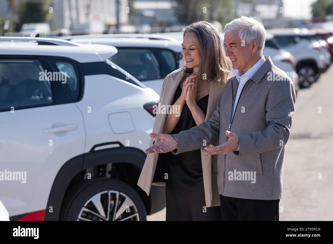 Mature Caucasian Couple Walks Past Cars Outdoors Choosing A New One