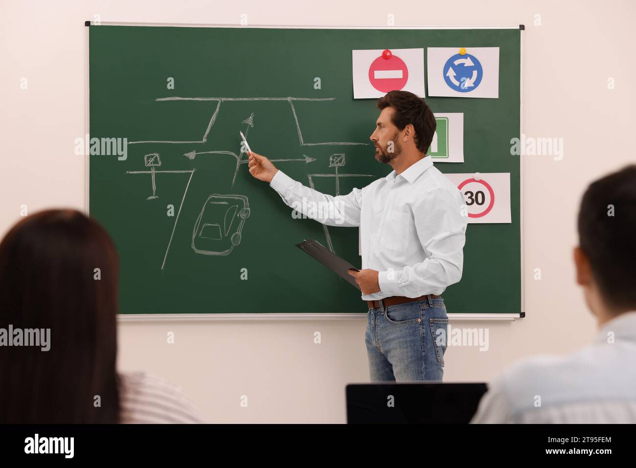 Teacher explaining traffic rules to audience during lesson in driving ...