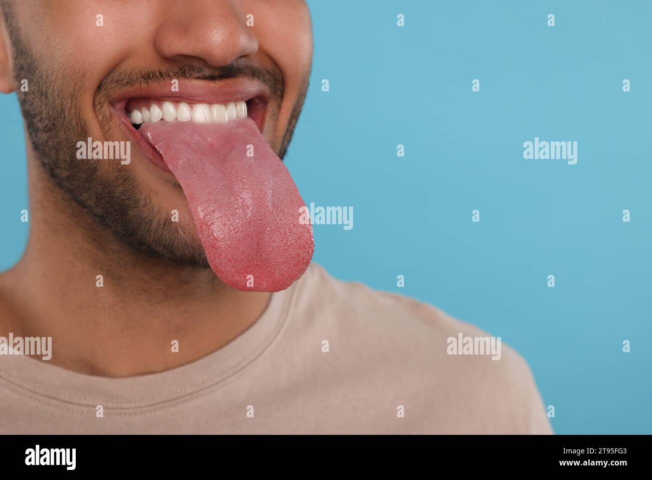 Man showing long tongue on light blue background, closeup Stock Photo ...
