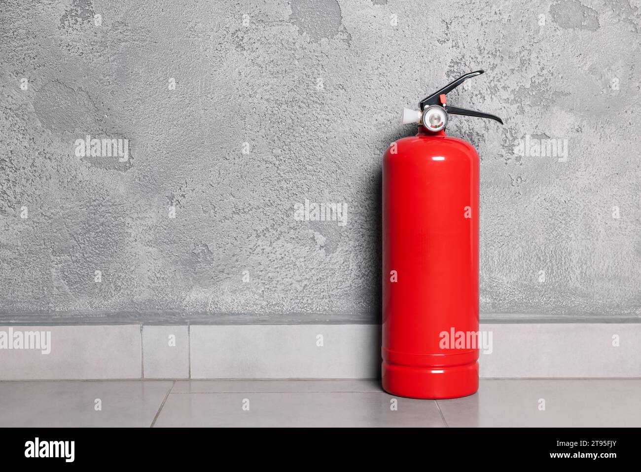Red fire extinguisher near grey wall, space for text Stock Photo - Alamy