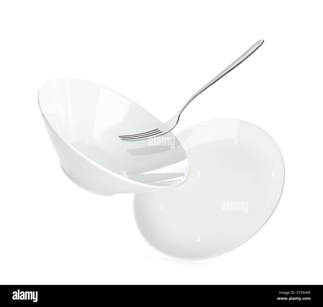 Clean dishes and fork falling on white background Stock Photo - Alamy