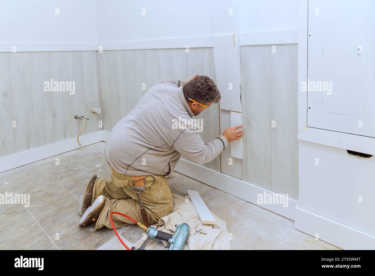 Contractor worker nailing wooden trim moldings at room Stock Photo - Alamy
