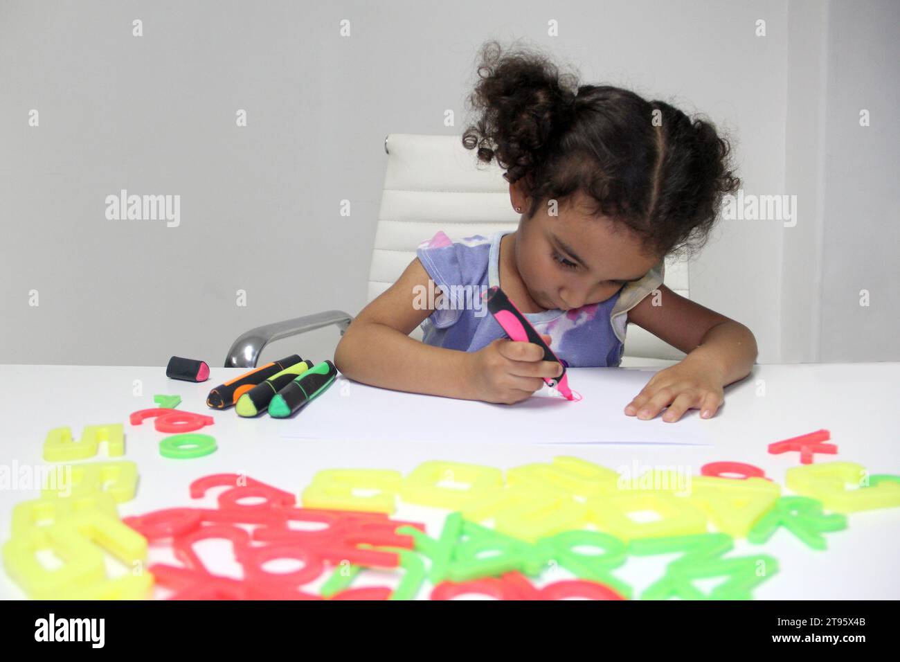 3-year-old Latina girl with brunette curly hair draws as a therapy tool ...