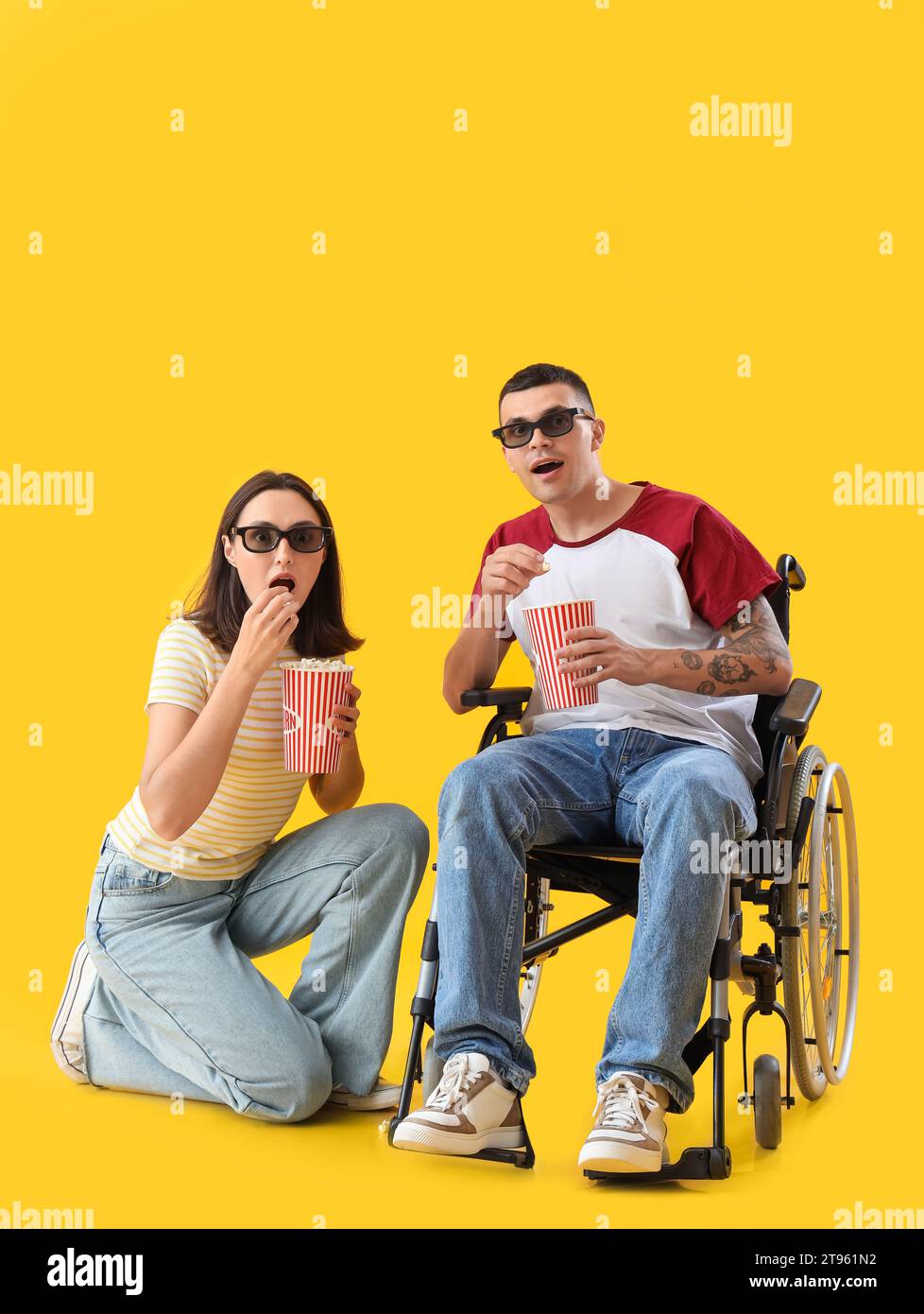 Young man in wheelchair and his wife with popcorn watching movie on ...