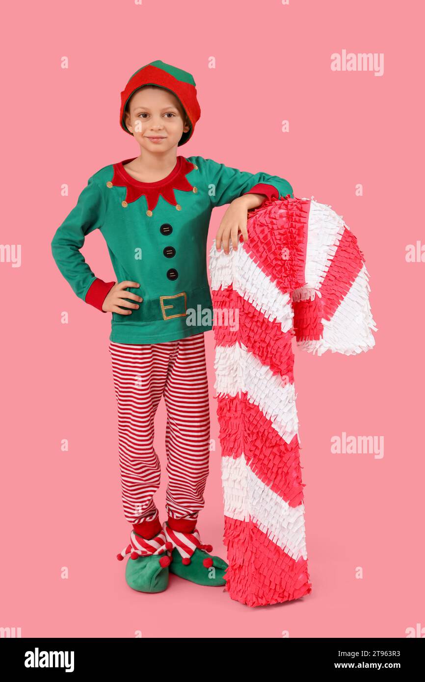 Cute little boy in elf's costume with candy cane pinata on pink ...