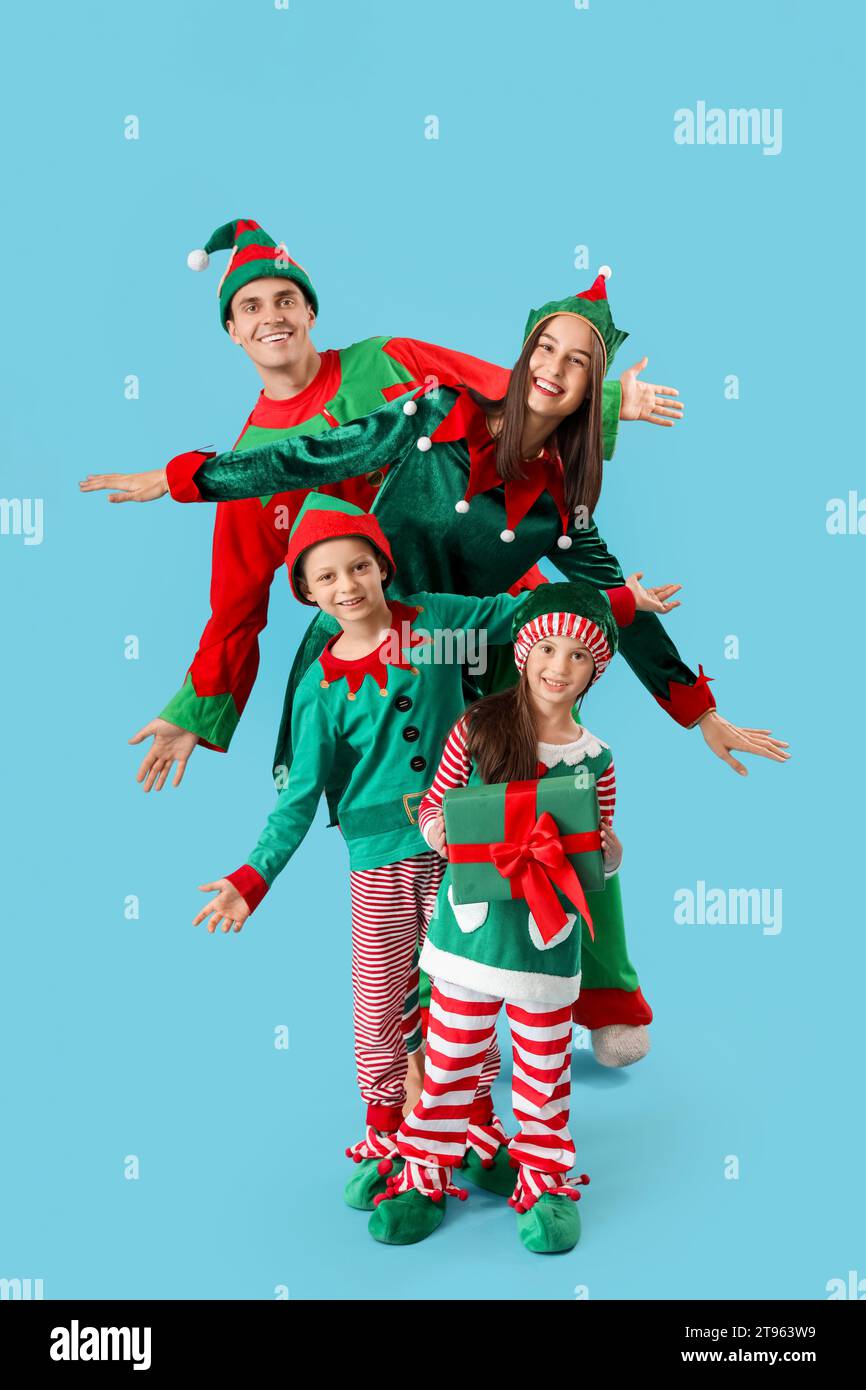 Happy family in elf's costumes with gift box having fun on blue ...