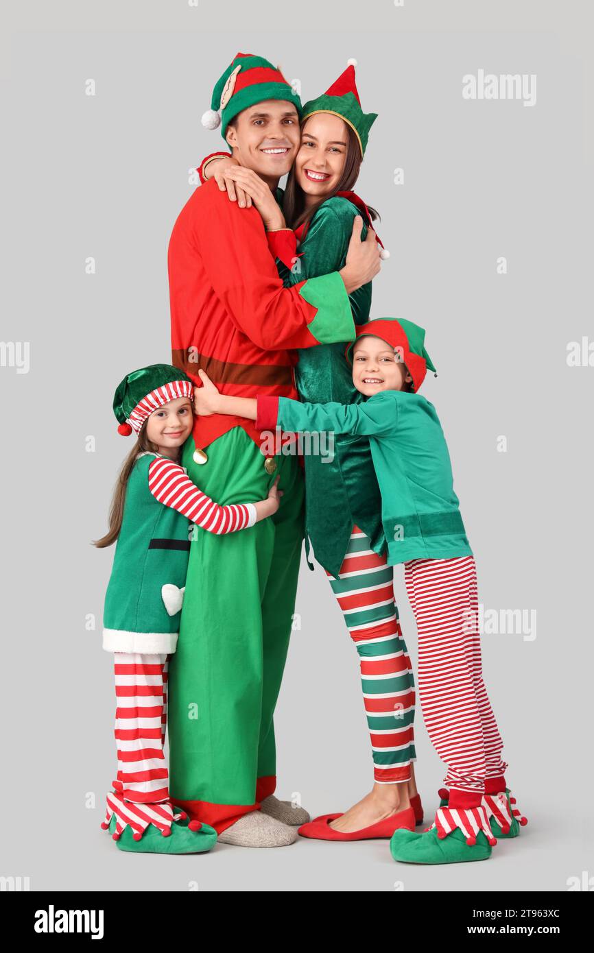 Happy family in elf's costumes hugging on grey background Stock Photo ...