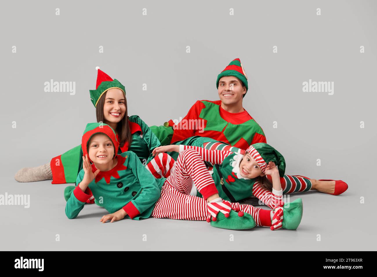 Happy family in elf's costumes on grey background Stock Photo - Alamy