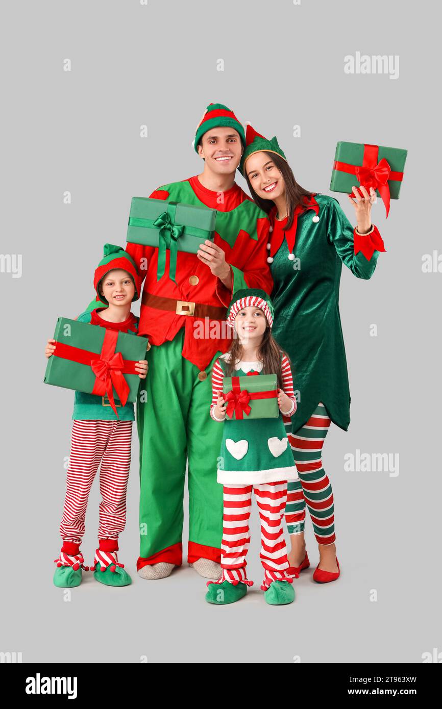 Happy family in elf's costumes with gift boxes on grey background Stock ...