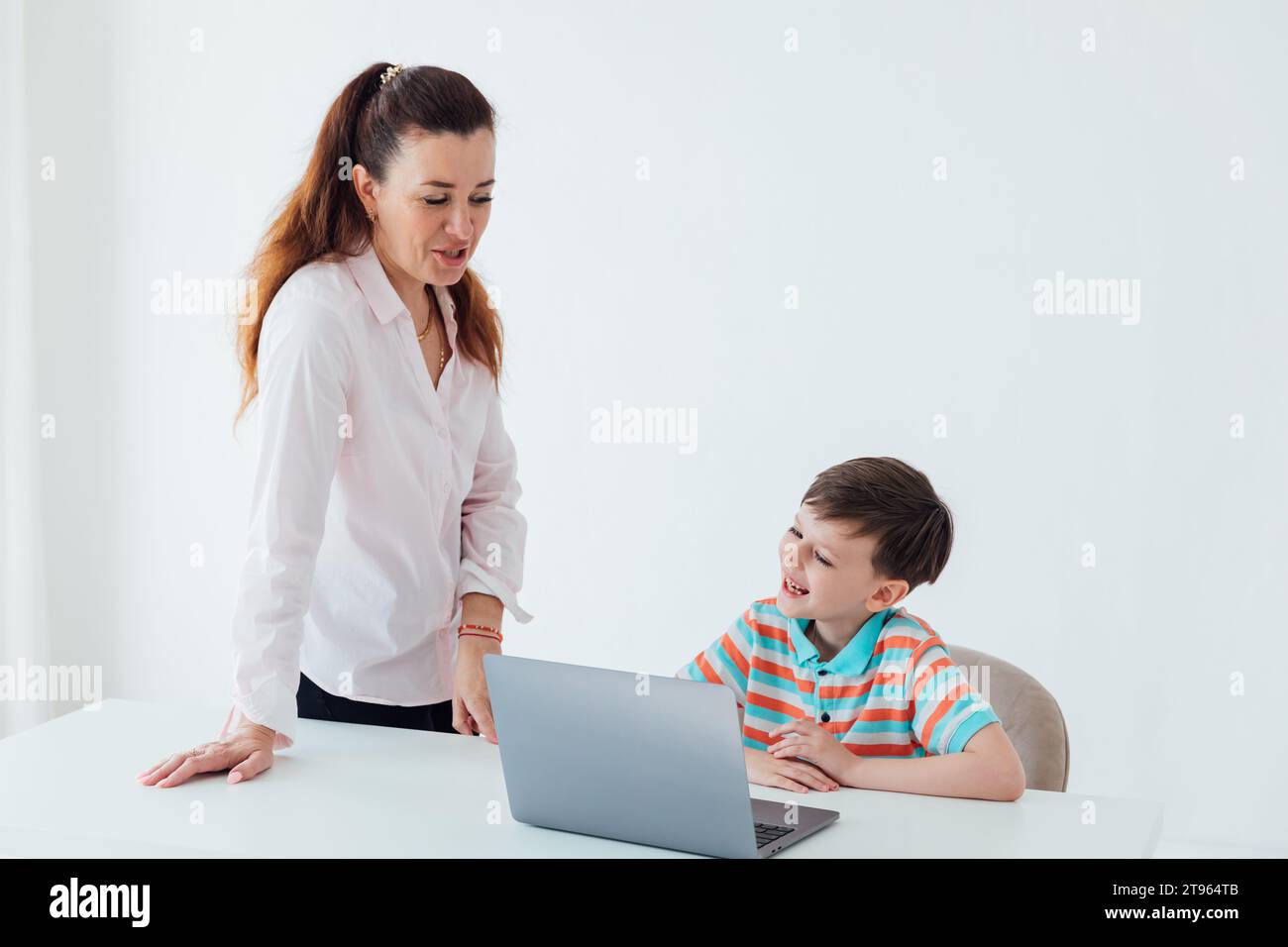 Female teacher teaching boy to use computer Stock Photo - Alamy