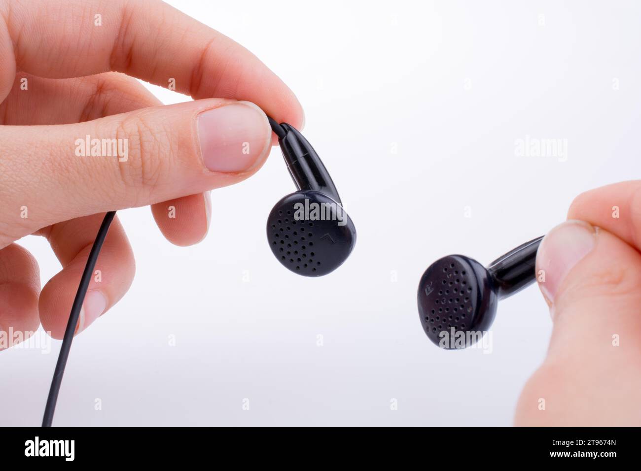 Hand holding a black earphone on a white background Stock Photo - Alamy