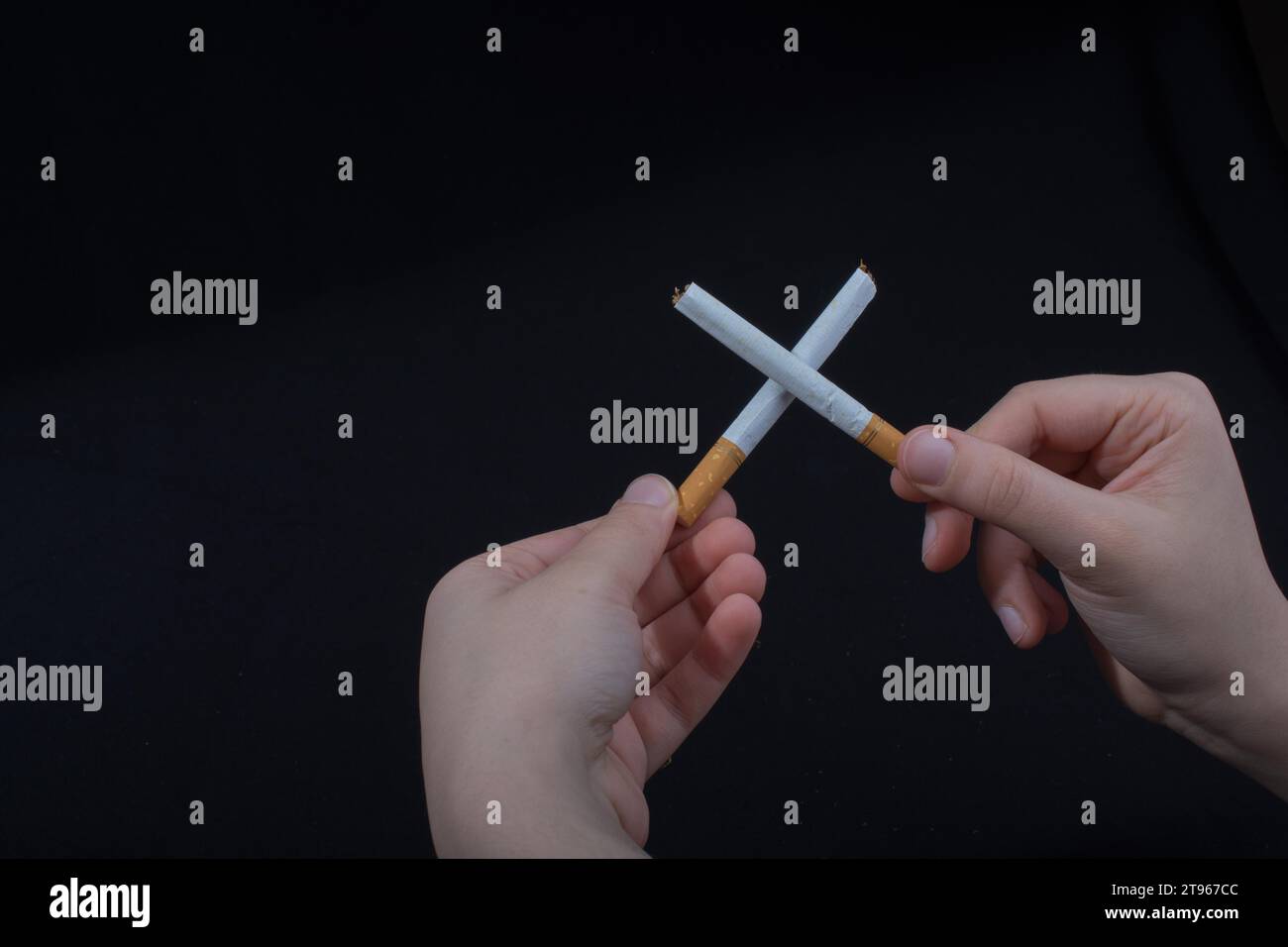 Hand is holding crossed cigarettes on black background Stock Photo - Alamy