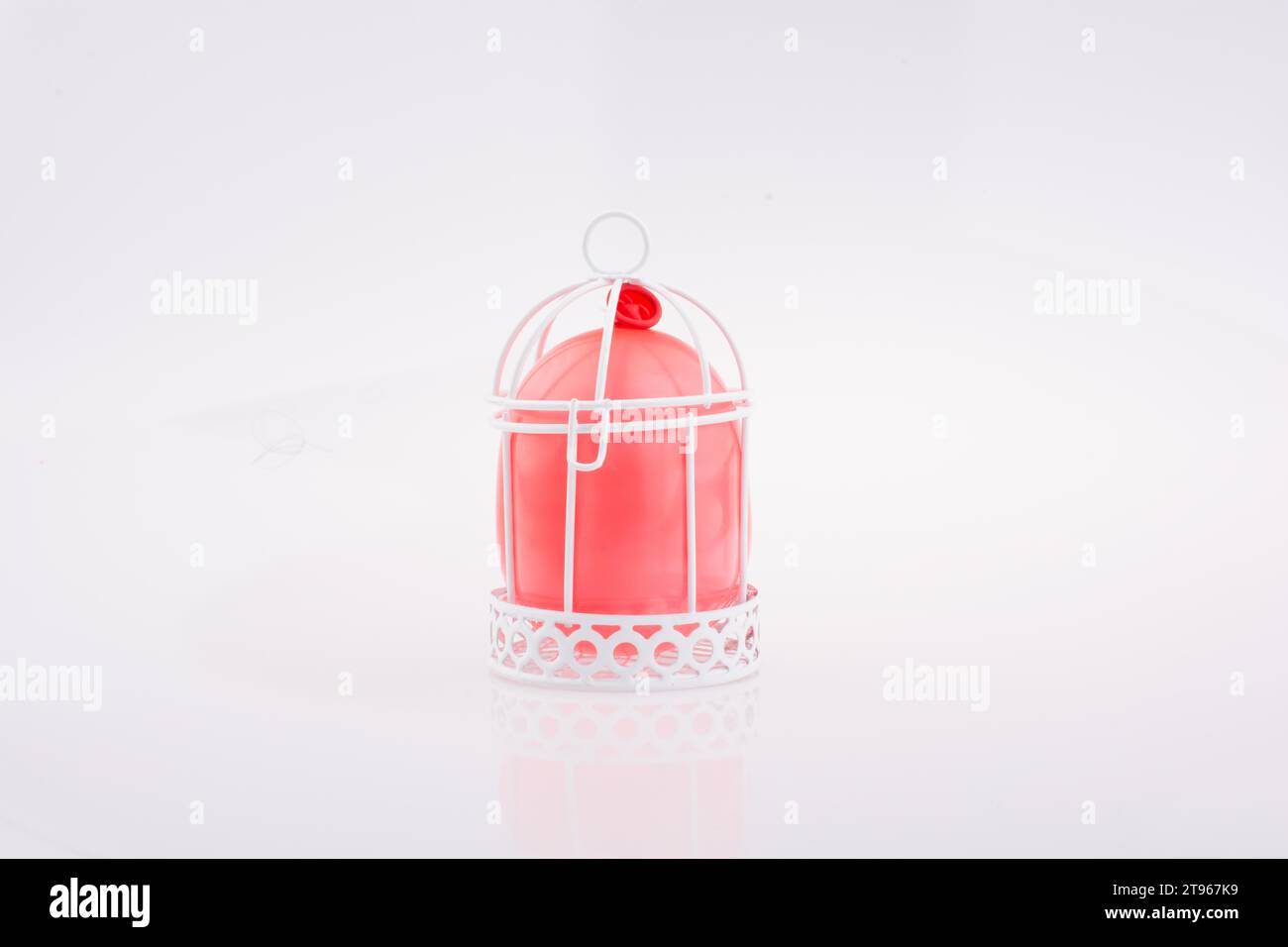 Little red balloon placed in a white color bird house with metal bars ...