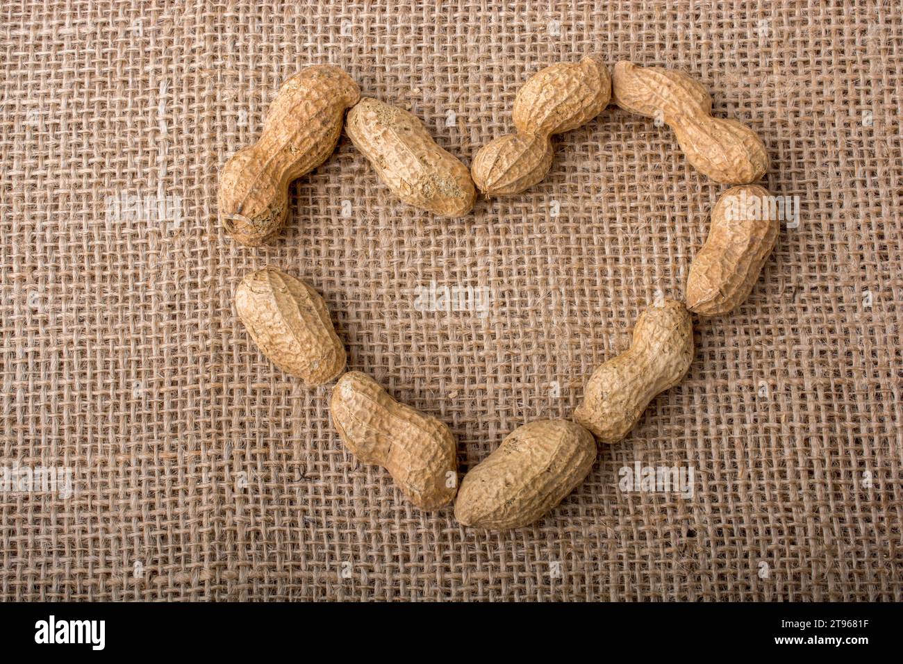 Peanuts form a heart shape on canvas background Stock Photo - Alamy