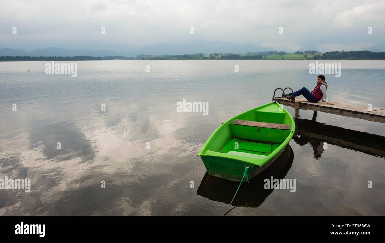 Woman 50+, wooden jetty, green rowing boat, Hopfensee, Hopfen am See ...