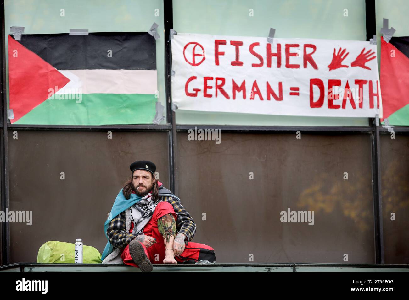 A Palestine Action activist sits on the edge of the glass roof where ...