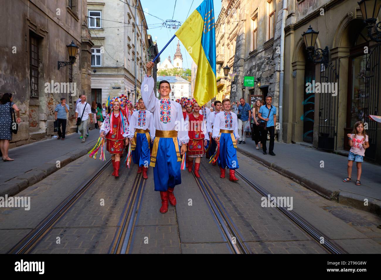 Ukrainian Folklore group lead by flag bearer walking down streets ...