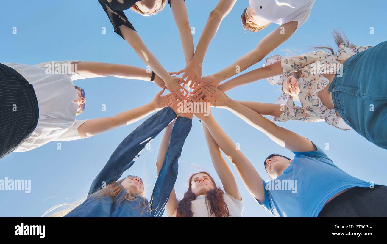 Friends putting their hands together in a sign of unity and teamwork ...