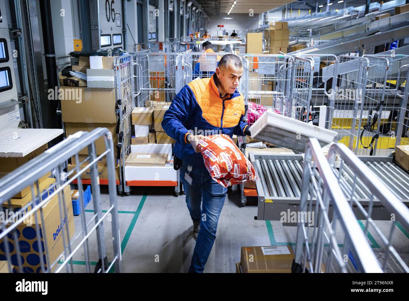WESTZAAN - PostNL employees at work in a parcel sorting center. In the ...