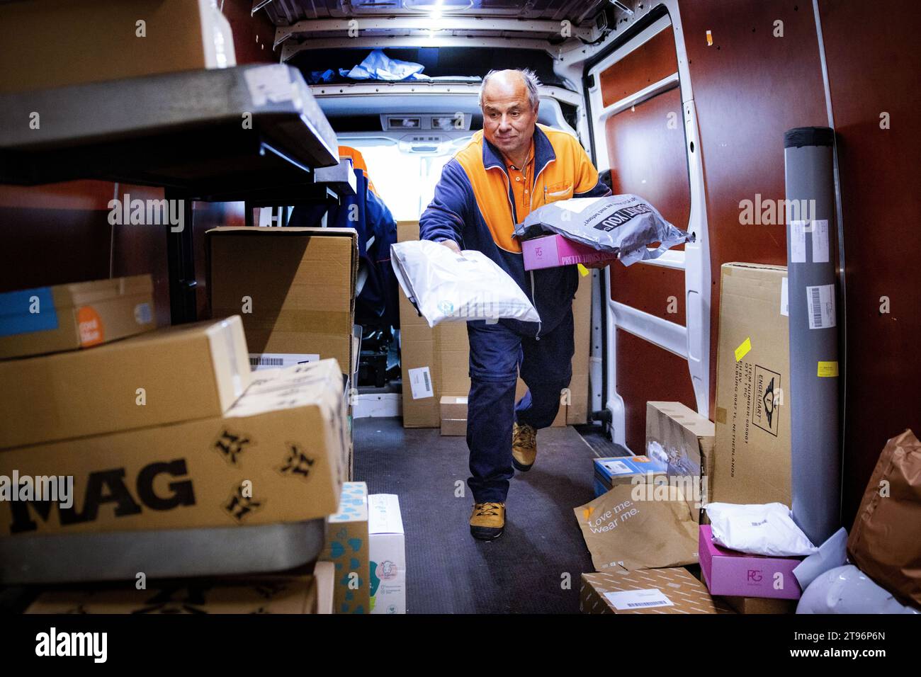 WESTZAAN - PostNL employees at work in a parcel sorting center. In the ...