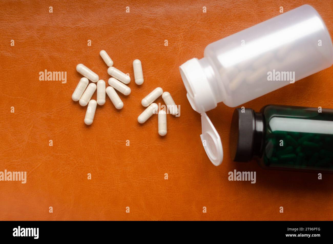 Pills spilling out of pill bottle on brown leather background. Focus on ...