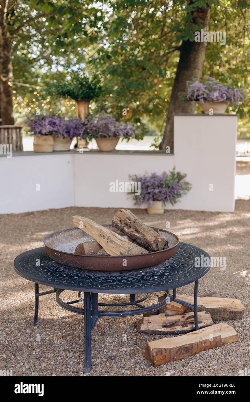 Open hearth with firewood installed on black wrought-iron table on ...