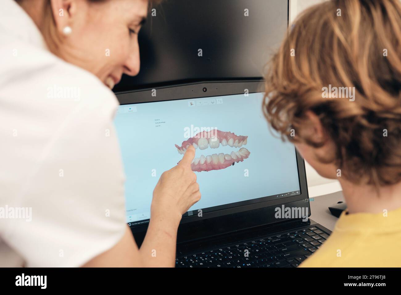 Crop positive female dentist demonstrating 3D teeth scan on laptop to ...