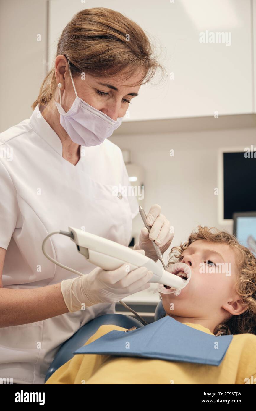 Professional female dentist in white uniform and protective mask ...