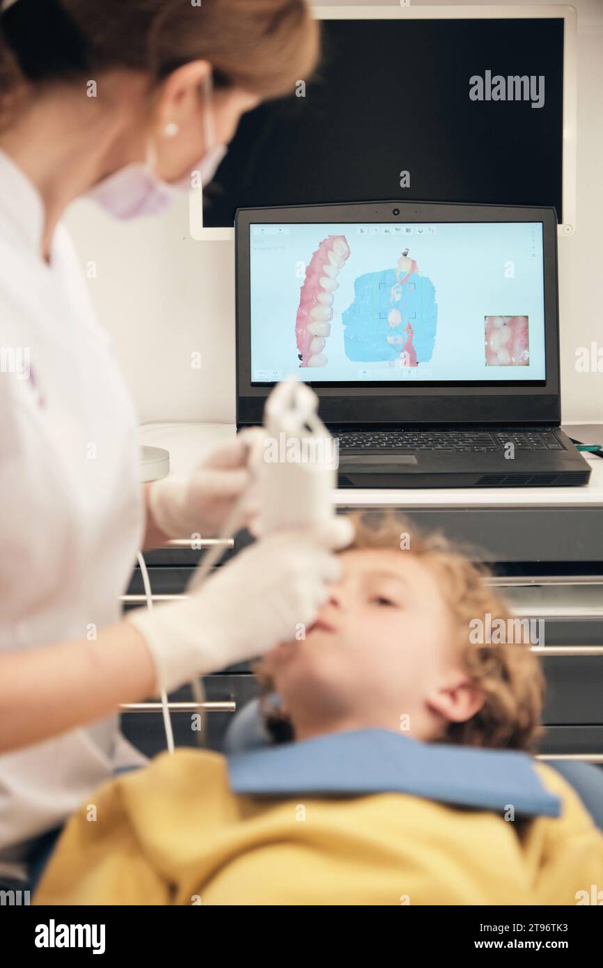 Crop anonymous female dentist making 3D teeth scanning to boy with ...