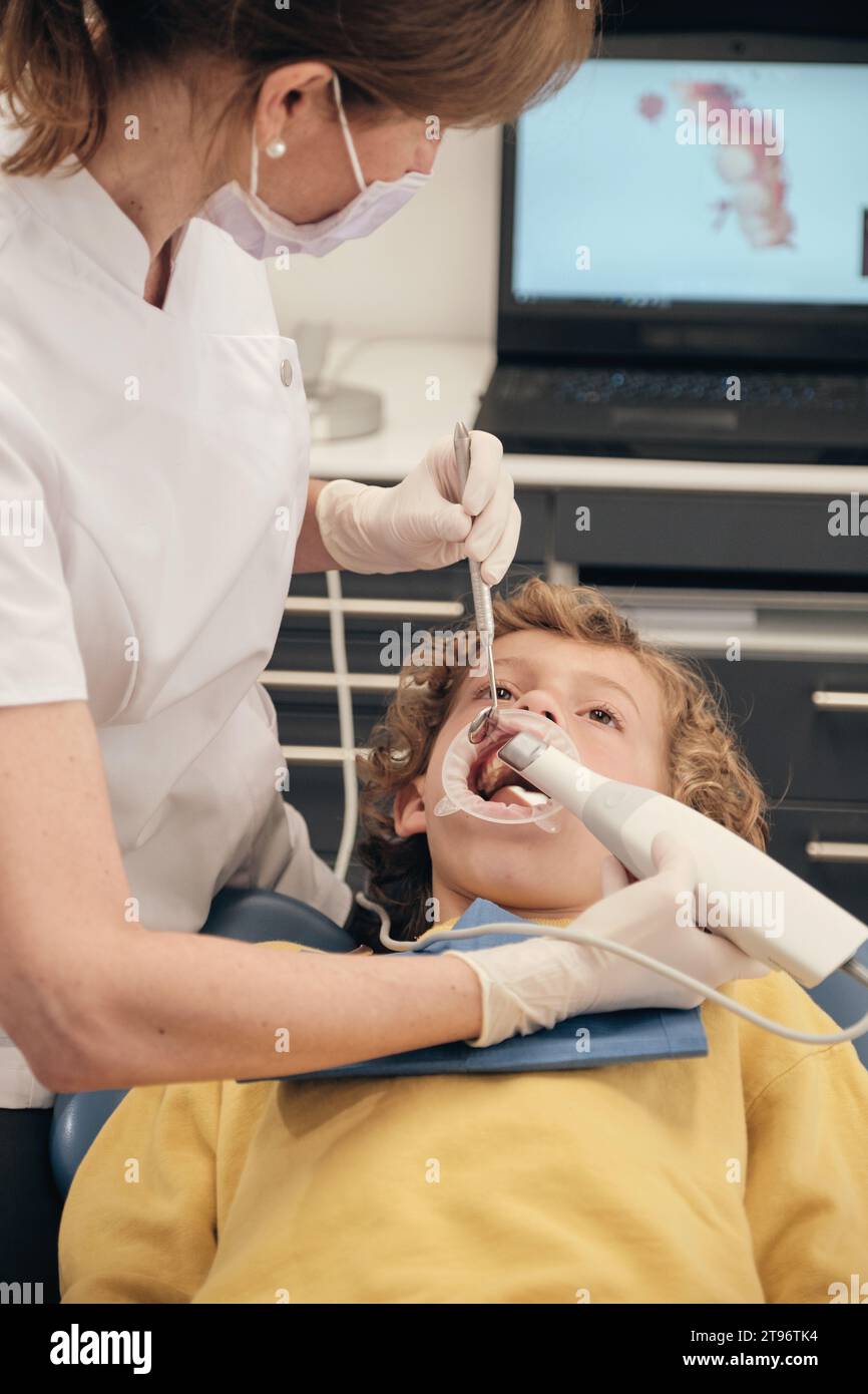 Crop anonymous female dentist using professional dental 3D scanner to ...