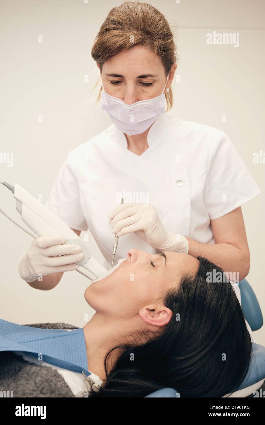 Female dentist in medical uniform and sterile gloves examining teeth of ...