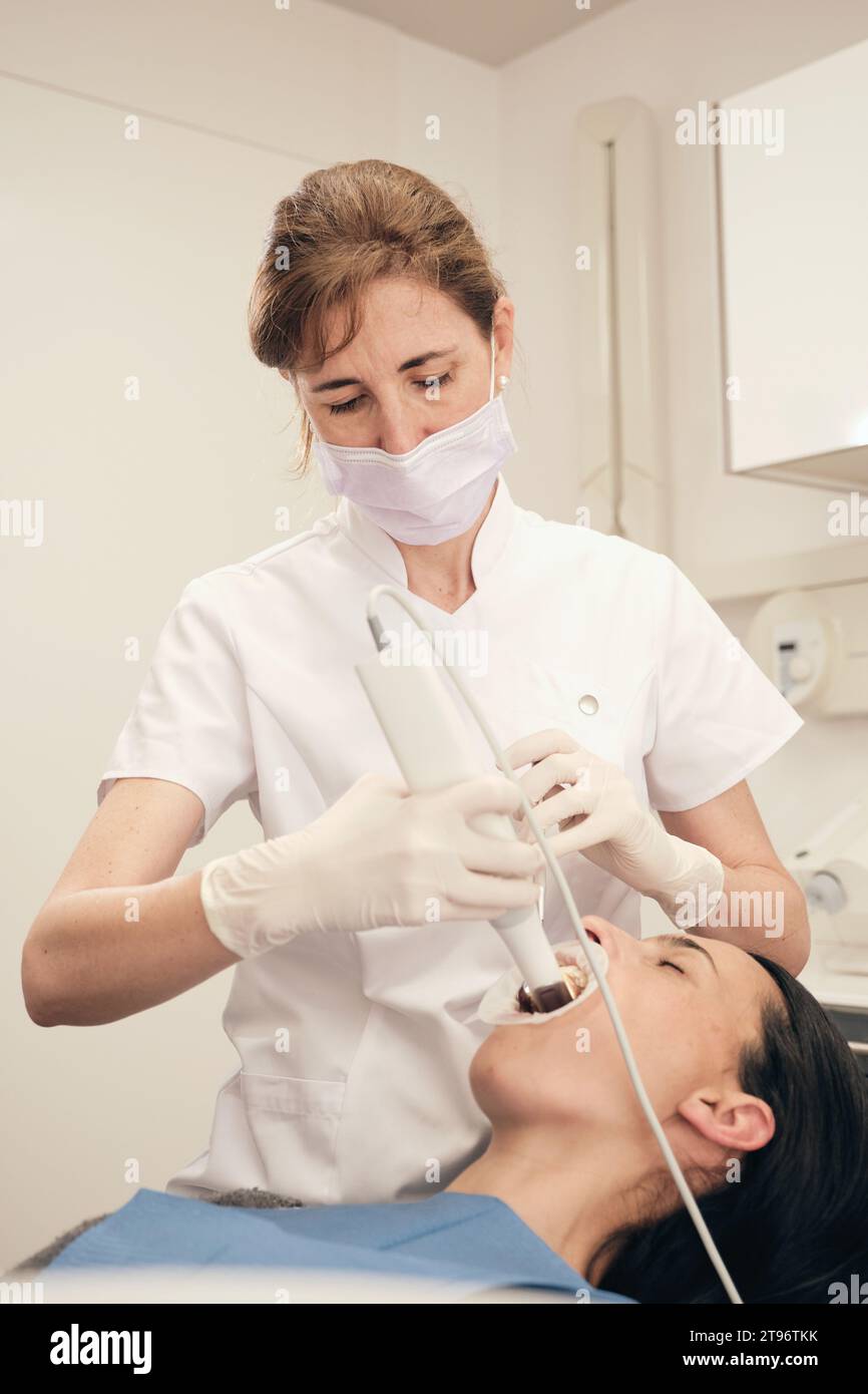Concentrated female orthodontist with professional tool wearing medical ...
