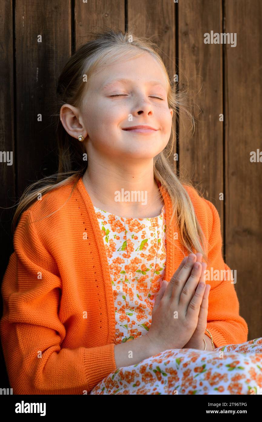 Concentrated blond child with closed eyes and namaste hands praying ...